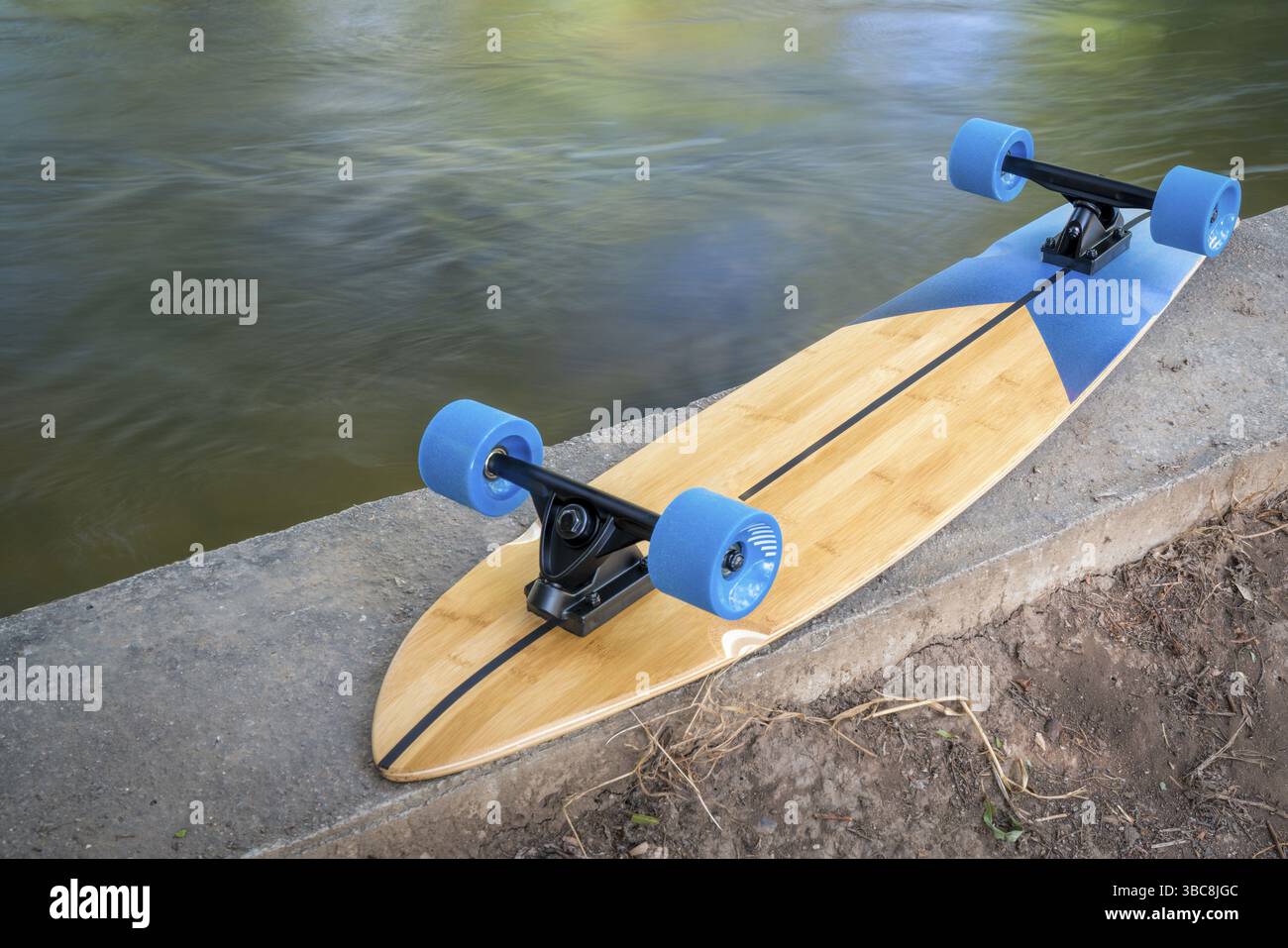 Cruising longboard with blue wheels on a river shore Stock Photo - Alamy