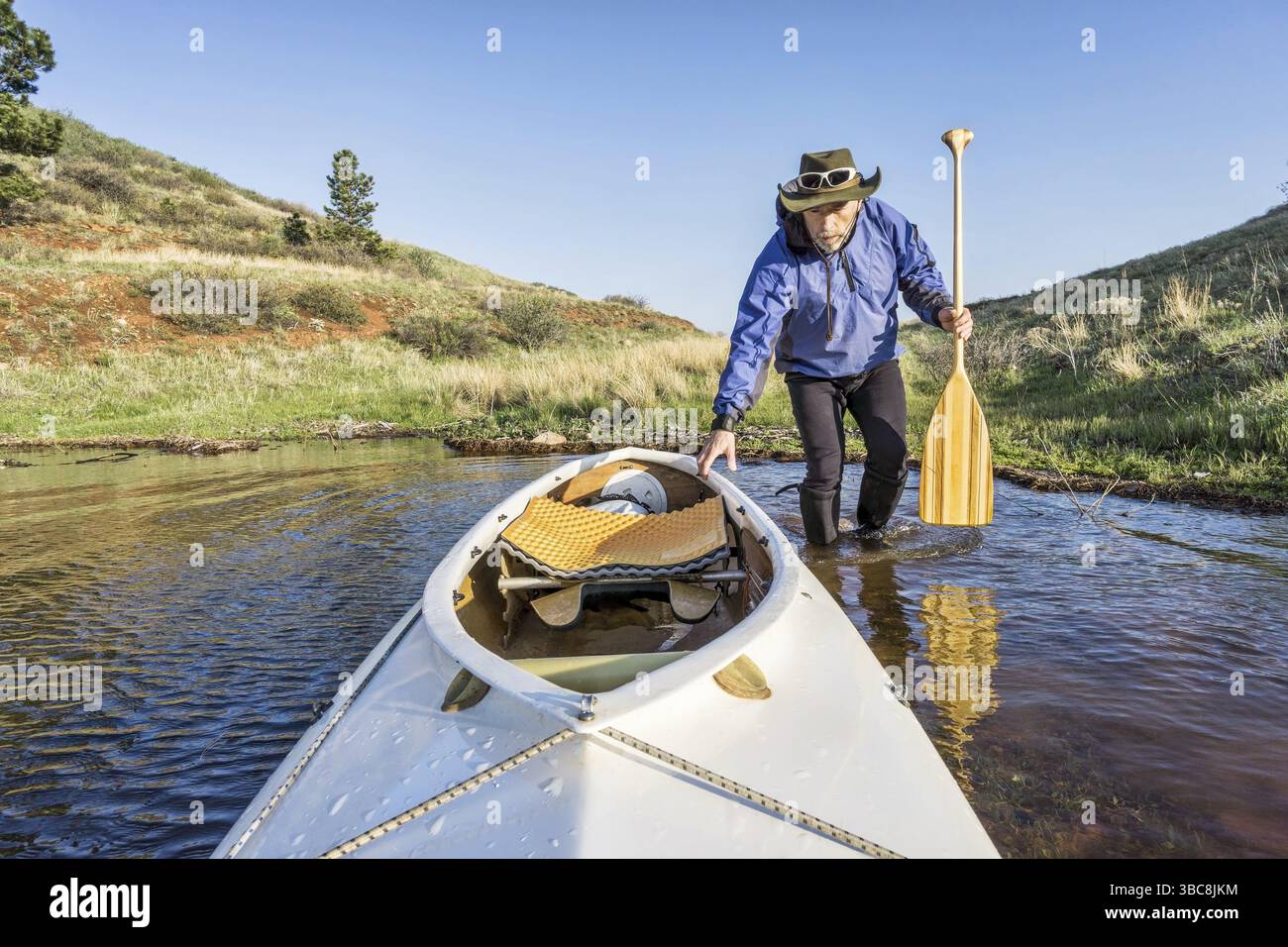 Senior paddler and decked expedition canoe on the shore of Horsetooth ...