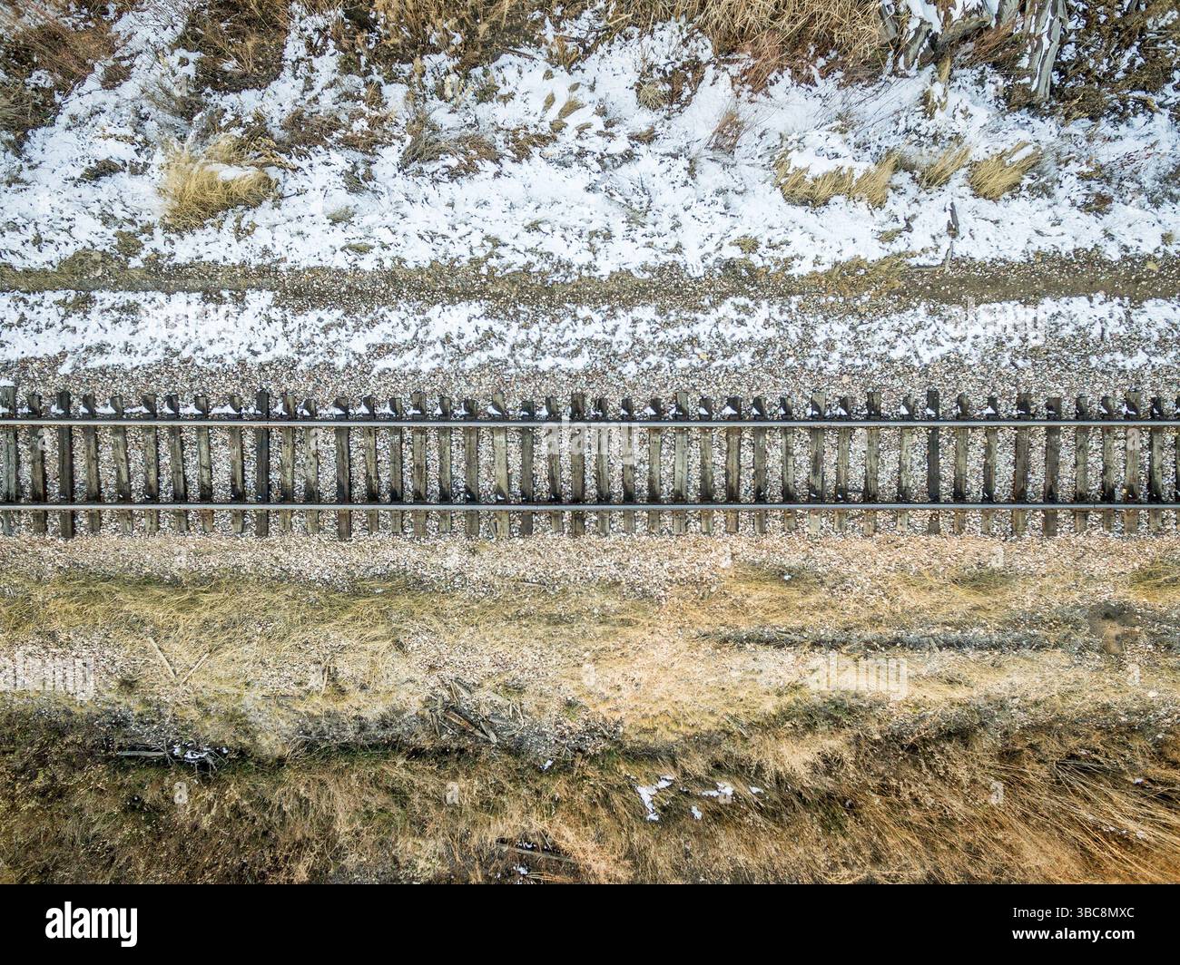 Aerial view of single railroad tracks in back country with some weeds ...