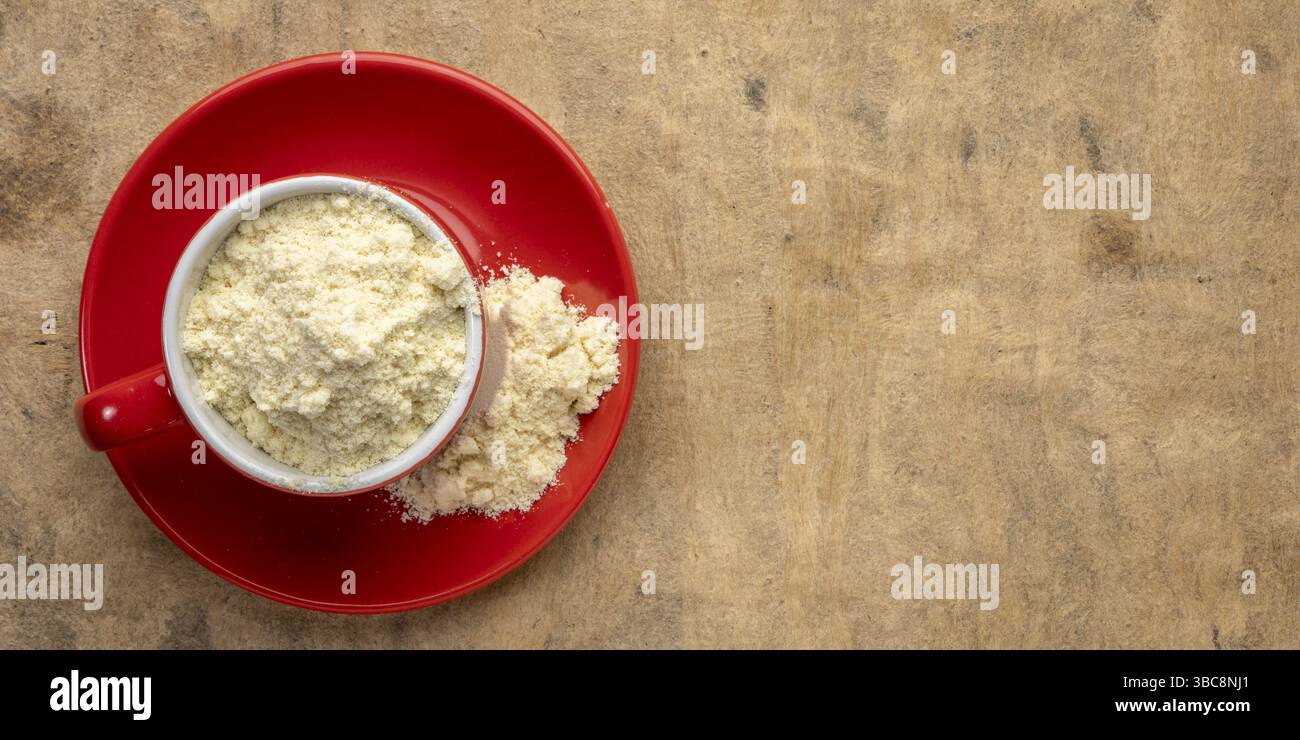 Whey protein powder in a red coffee cup against textured bark paper ...