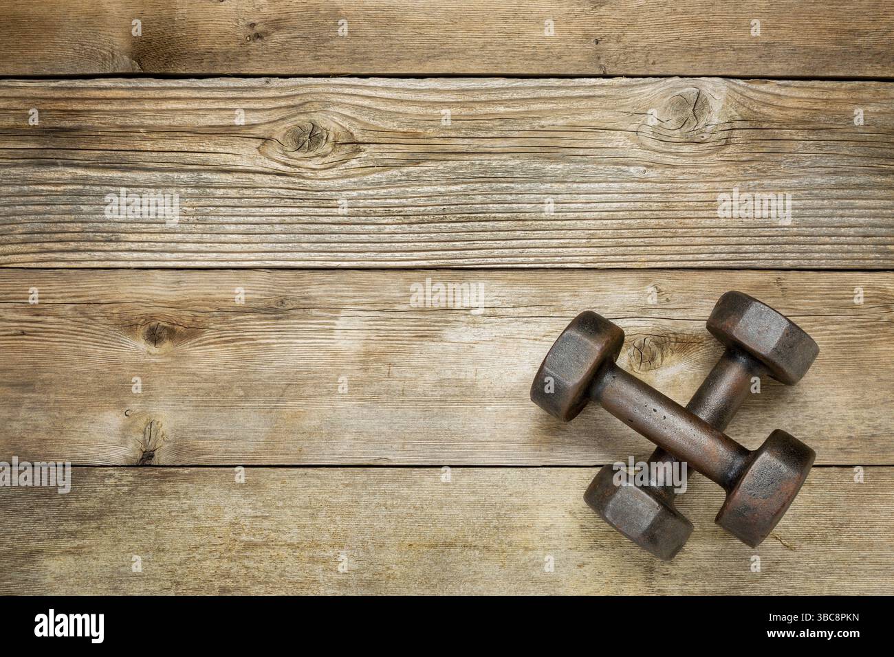 A pair of vintage iron rusty dumbbells on a weathered wood background ...