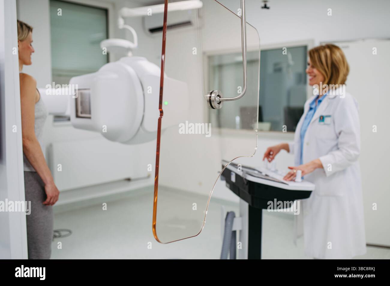 Female patient undergoing dynamic X-ray scan using tilting fluoroscopy ...