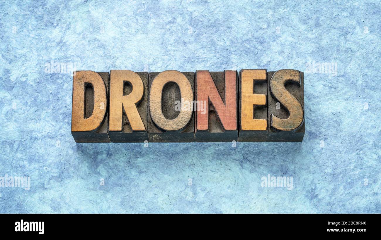 Drones word abstract in vintage letterpress wood type against blue ...