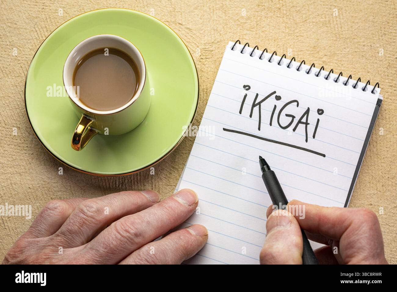 Ikigai, a reason for being - man hand writing a note with a black ...