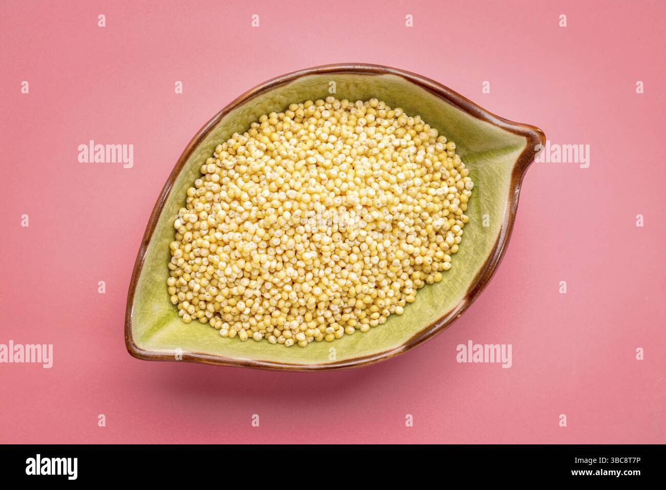 Gluten free hulled millet grain in a ceramic leaf shpaed bowl against ...