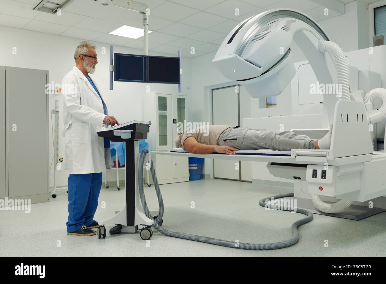Male patient undergoing X-ray examination using tilting radiographic ...
