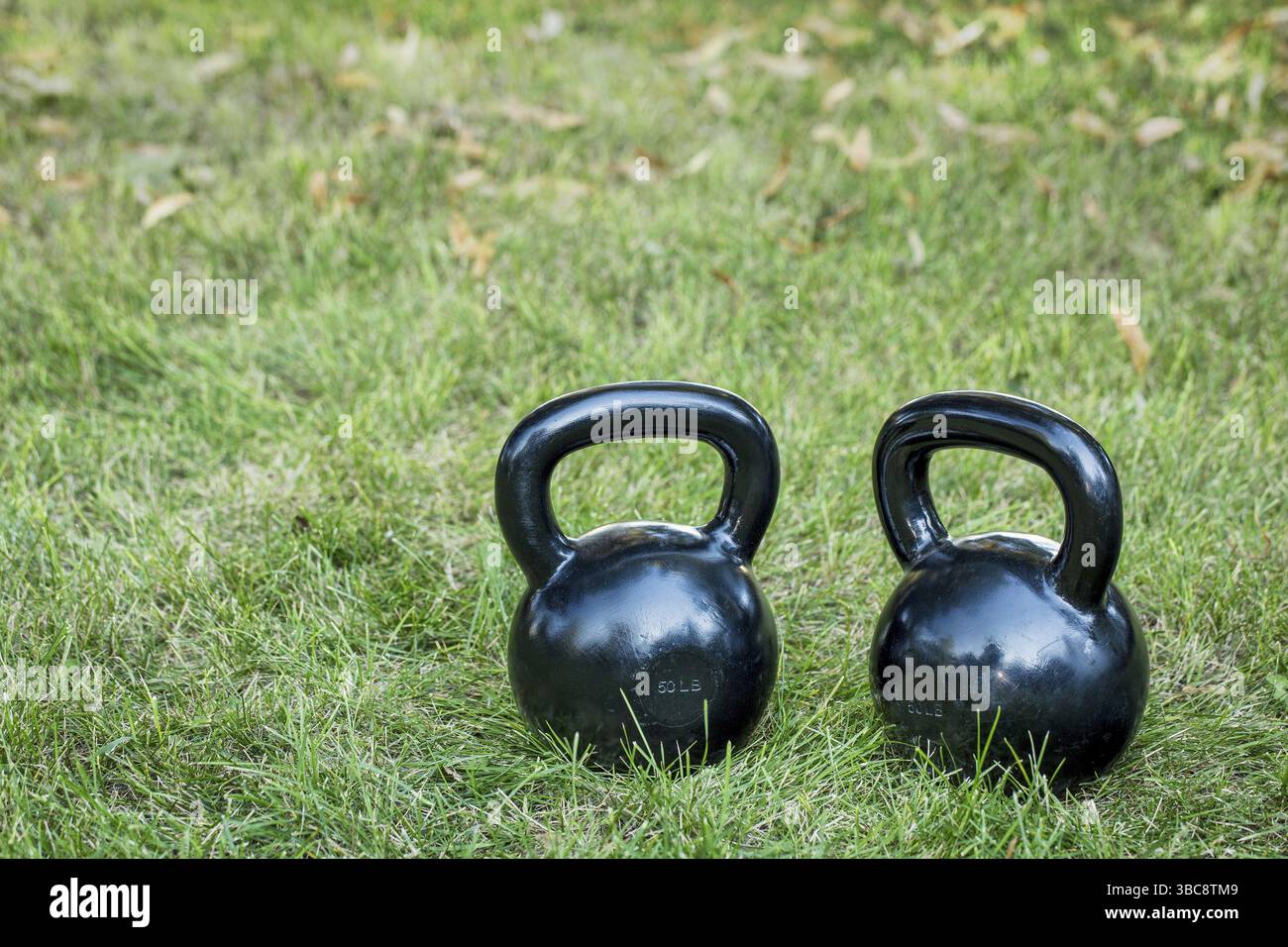 Two heavy iron kettlebells on a lawn - backyard fitness concept Stock ...