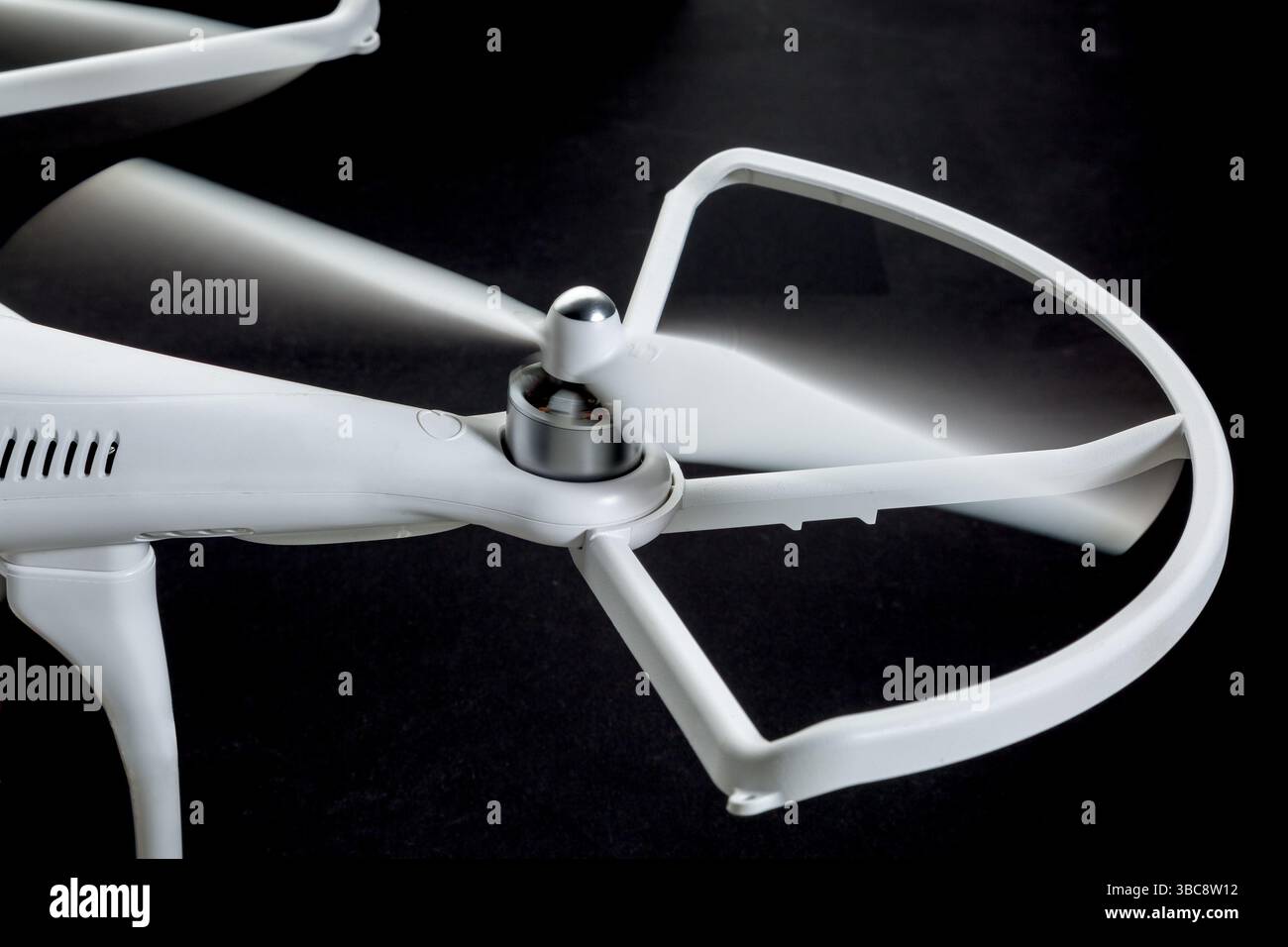 Rotating propeller of a white quadcopter drone against black background ...