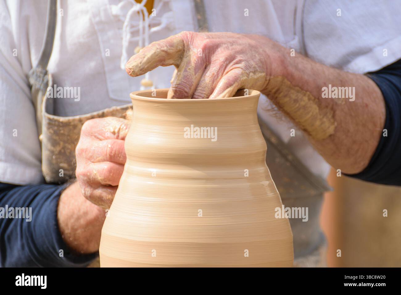 hands of a craftsman molding an earthenware clay vessel on a potter's ...