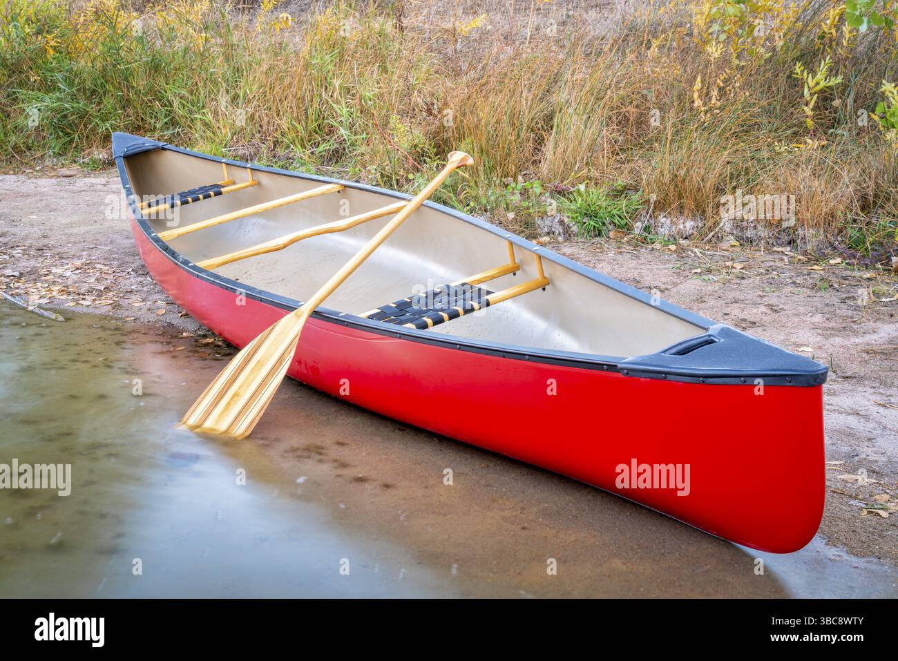 Red tandem canoe with a wooden paddle on a lake shore Stock Photo - Alamy