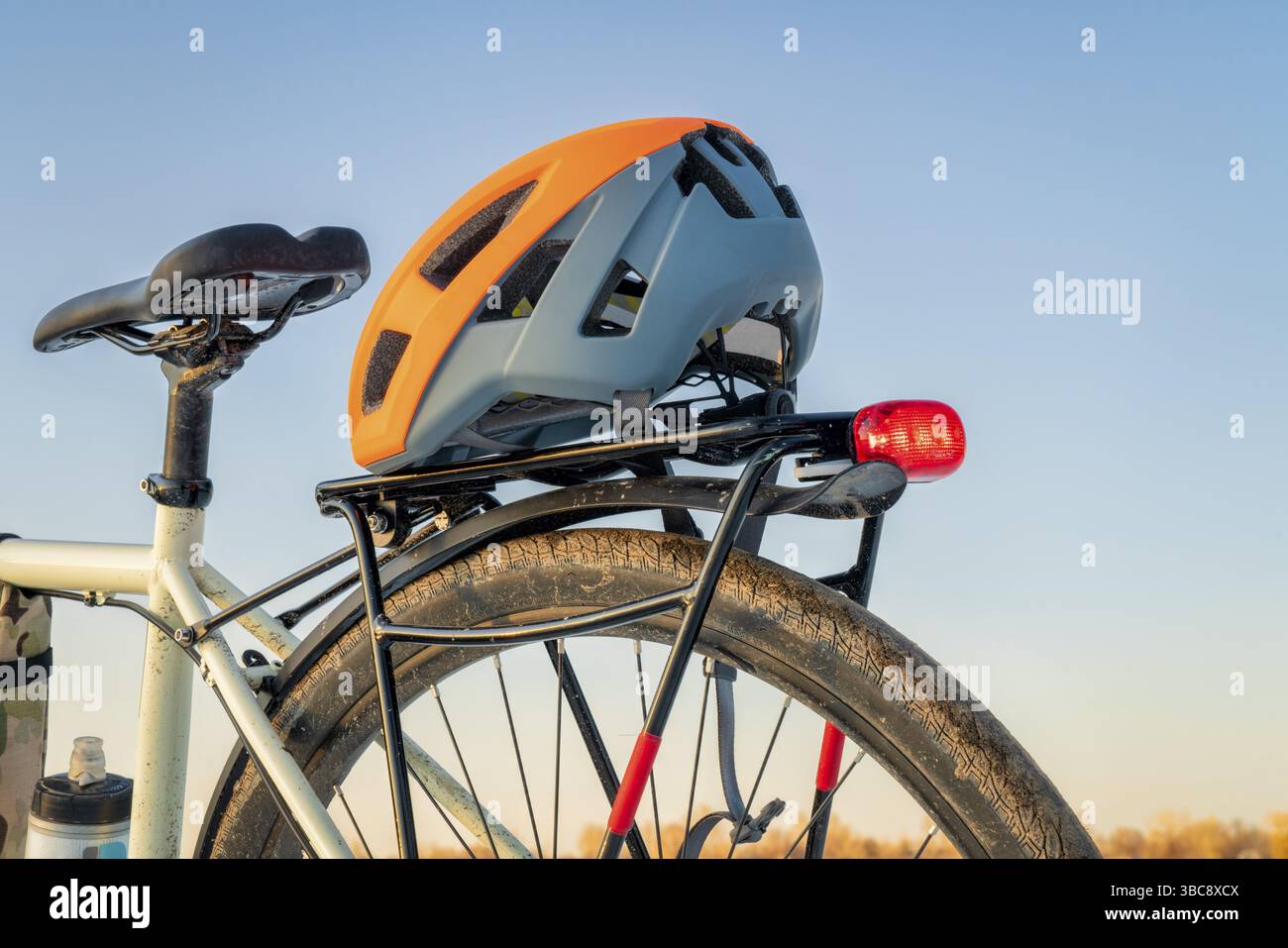 Biking helmet on racks of a muddy touring bike with a red tail light ...