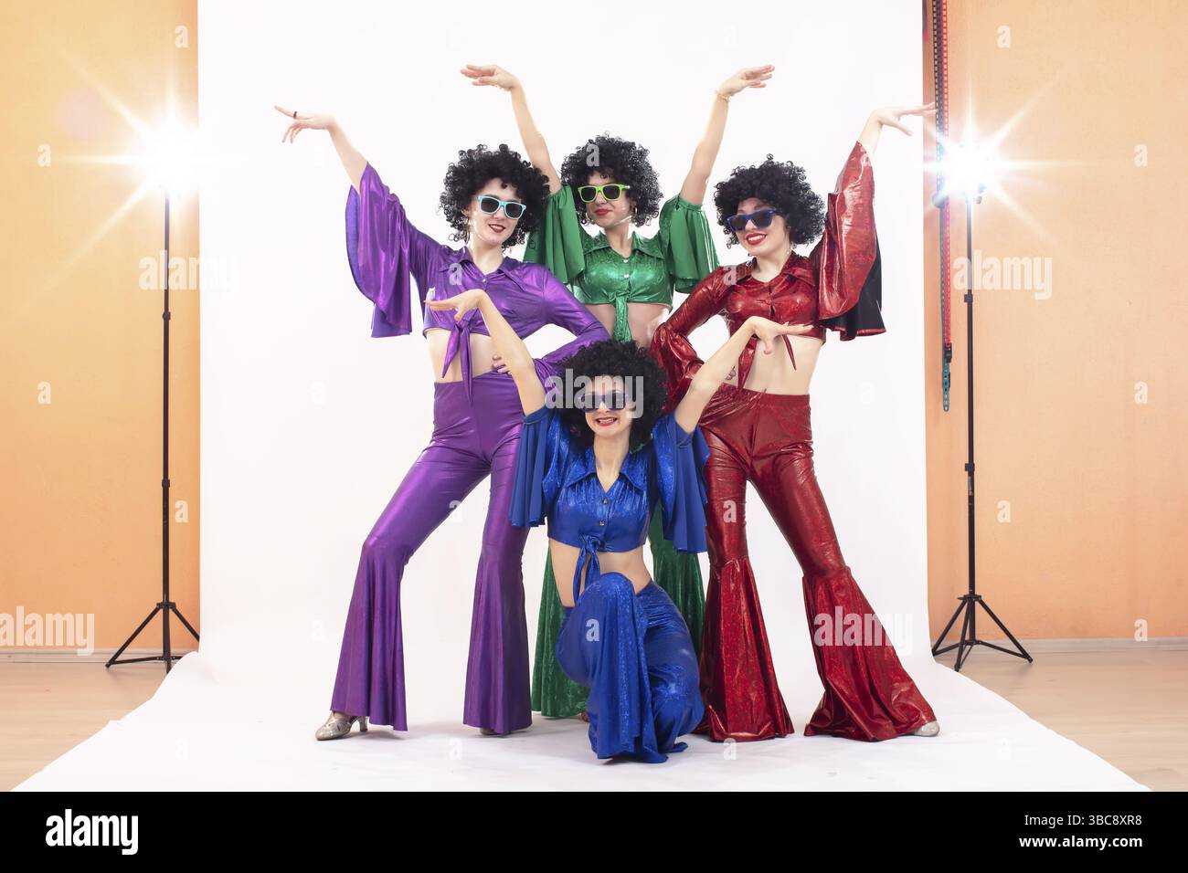 A group of girls in colourful suits and afro wigs pose in a photo ...