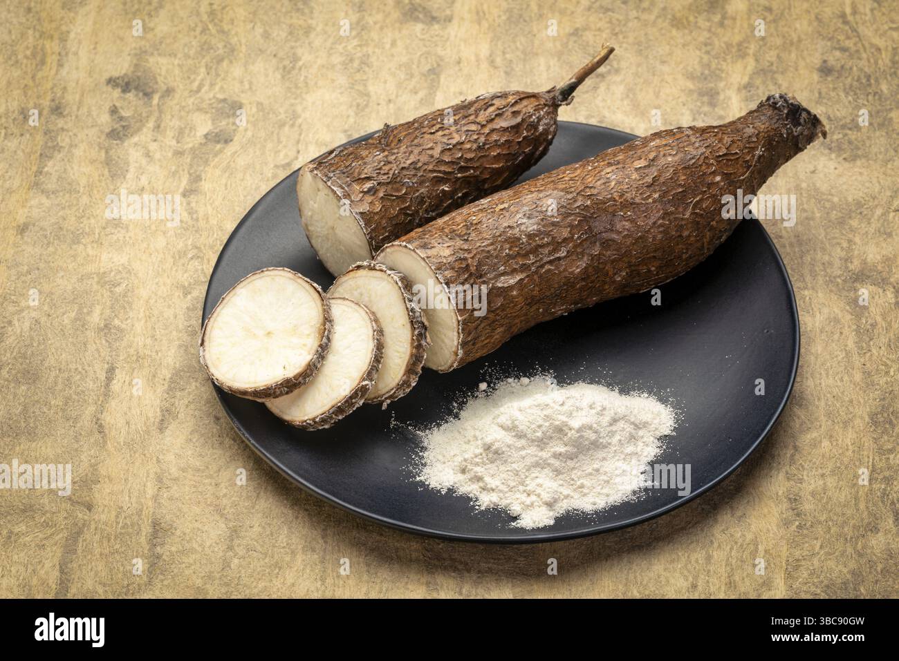 Cut and sliced yuca cassava root and flour on a black plate Stock Photo ...