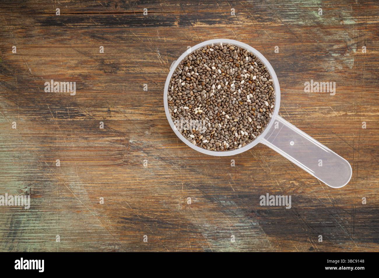 Top view of measuring scoop of chia seeds against grunge painted wood ...