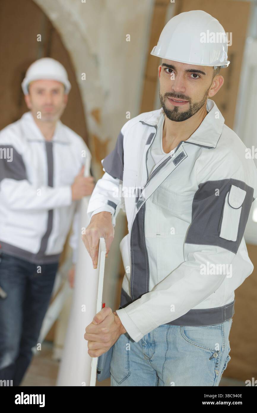 portrait of plasterer carrying a board Stock Photo - Alamy