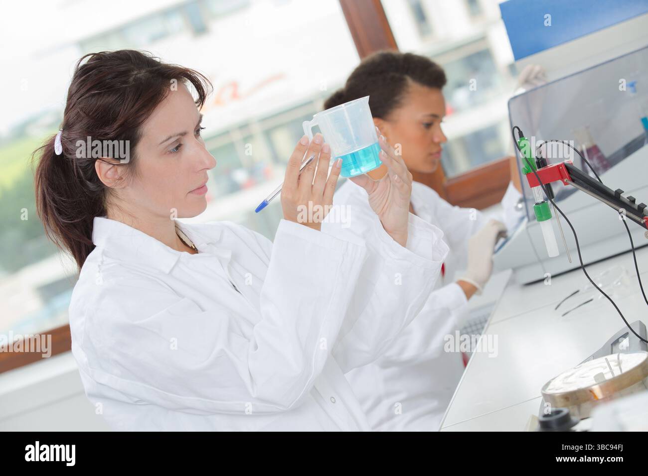 assistants adjust device for measuring liquid in chemical lab Stock ...