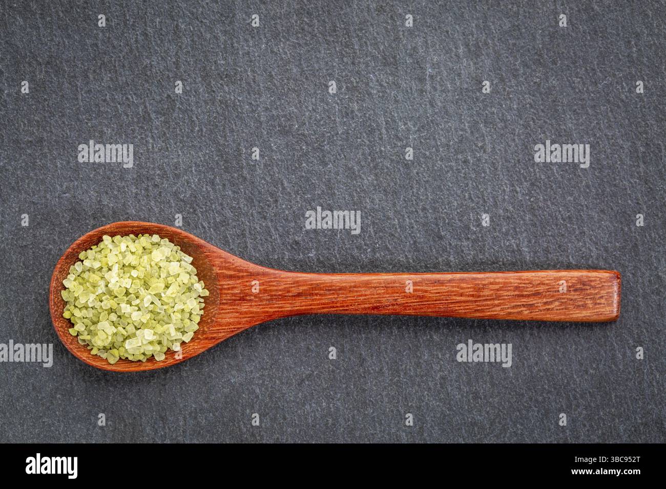 Matcha green tea salt in wooden tablespoon against gray slate stone ...
