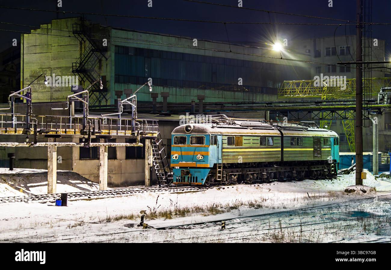 Nighttime view of an old Soviet locomotive parked on snowy tracks at ...