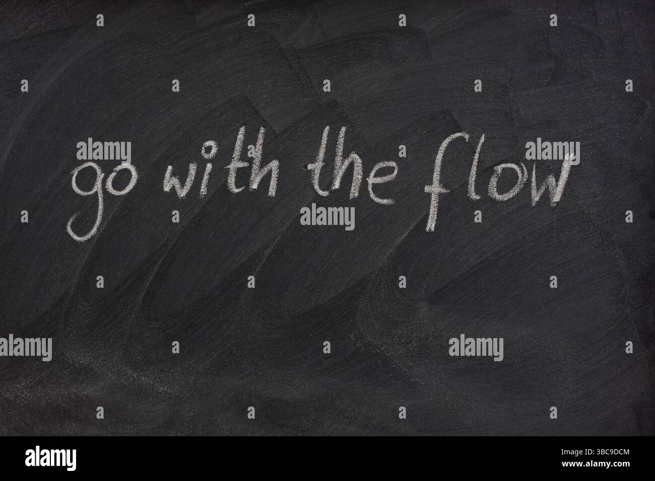 Go with the flow phrase handwritten with white chalk on blackboard with ...