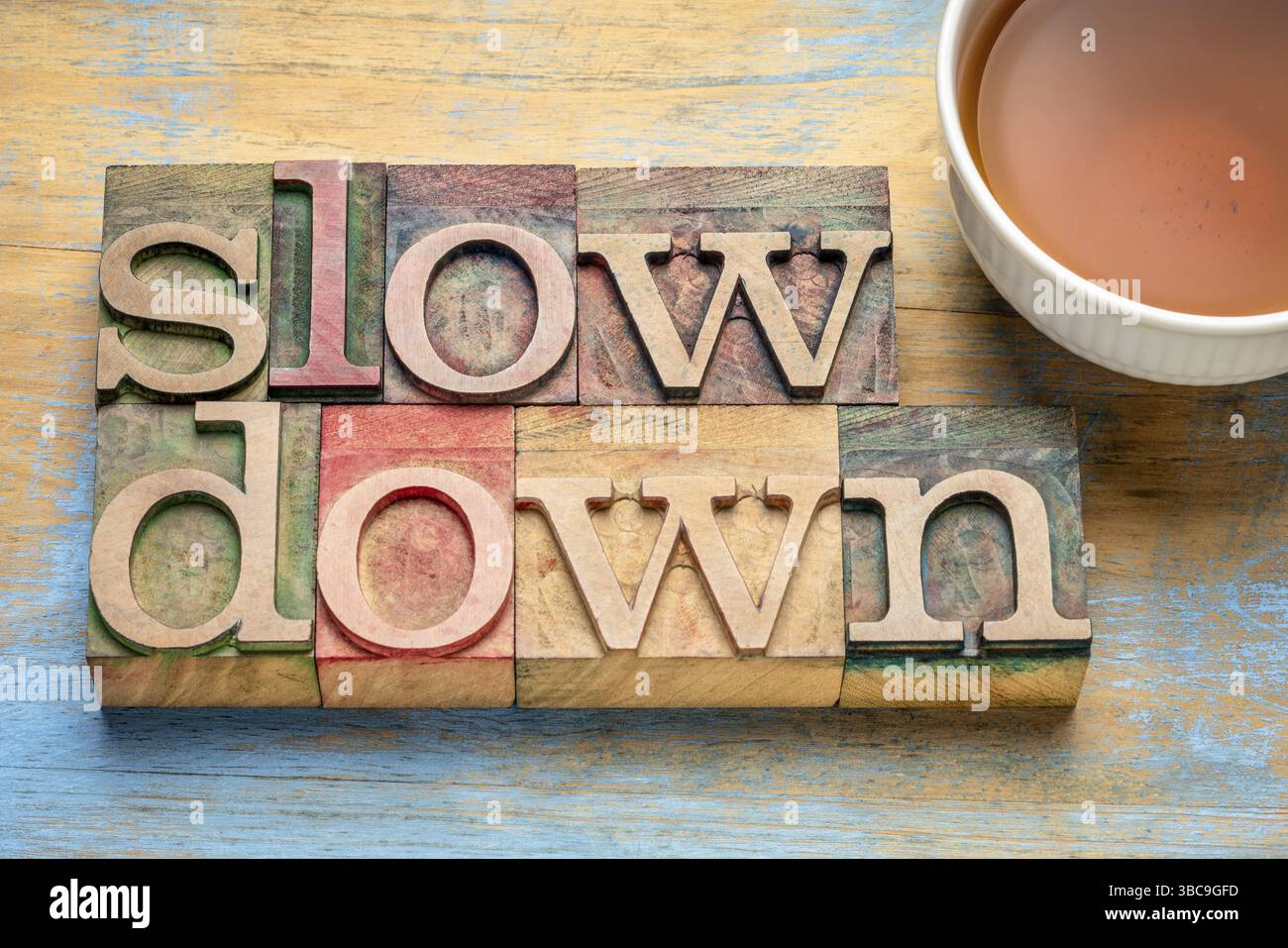 Slow down - word abstract in letterpress wood type blocks with a cup of ...