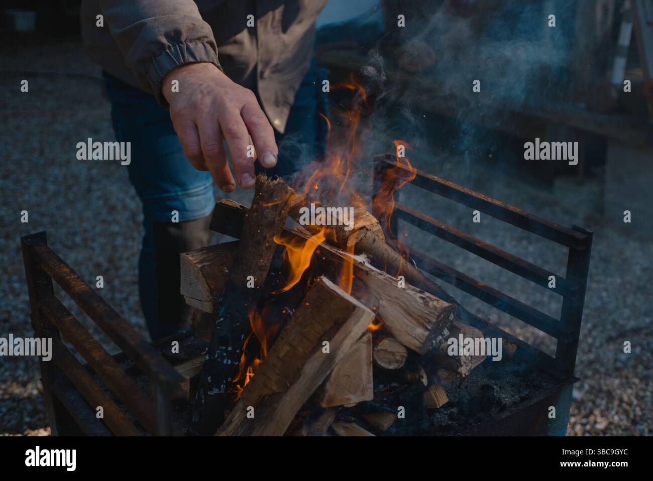 Hand of a working man putting firewood into burning fire Stock Photo ...