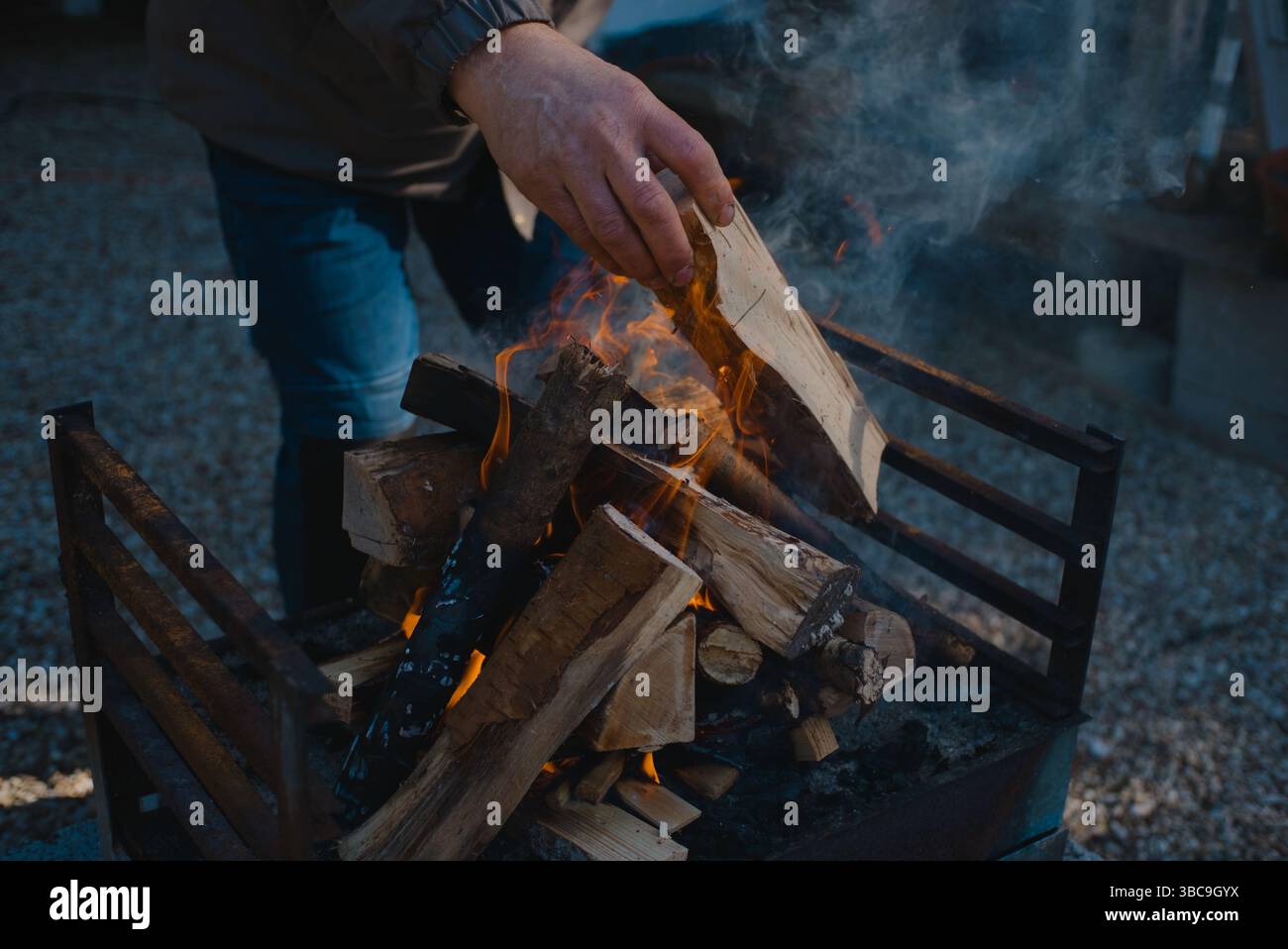 Hand of a working man putting firewood into burning fire Stock Photo ...