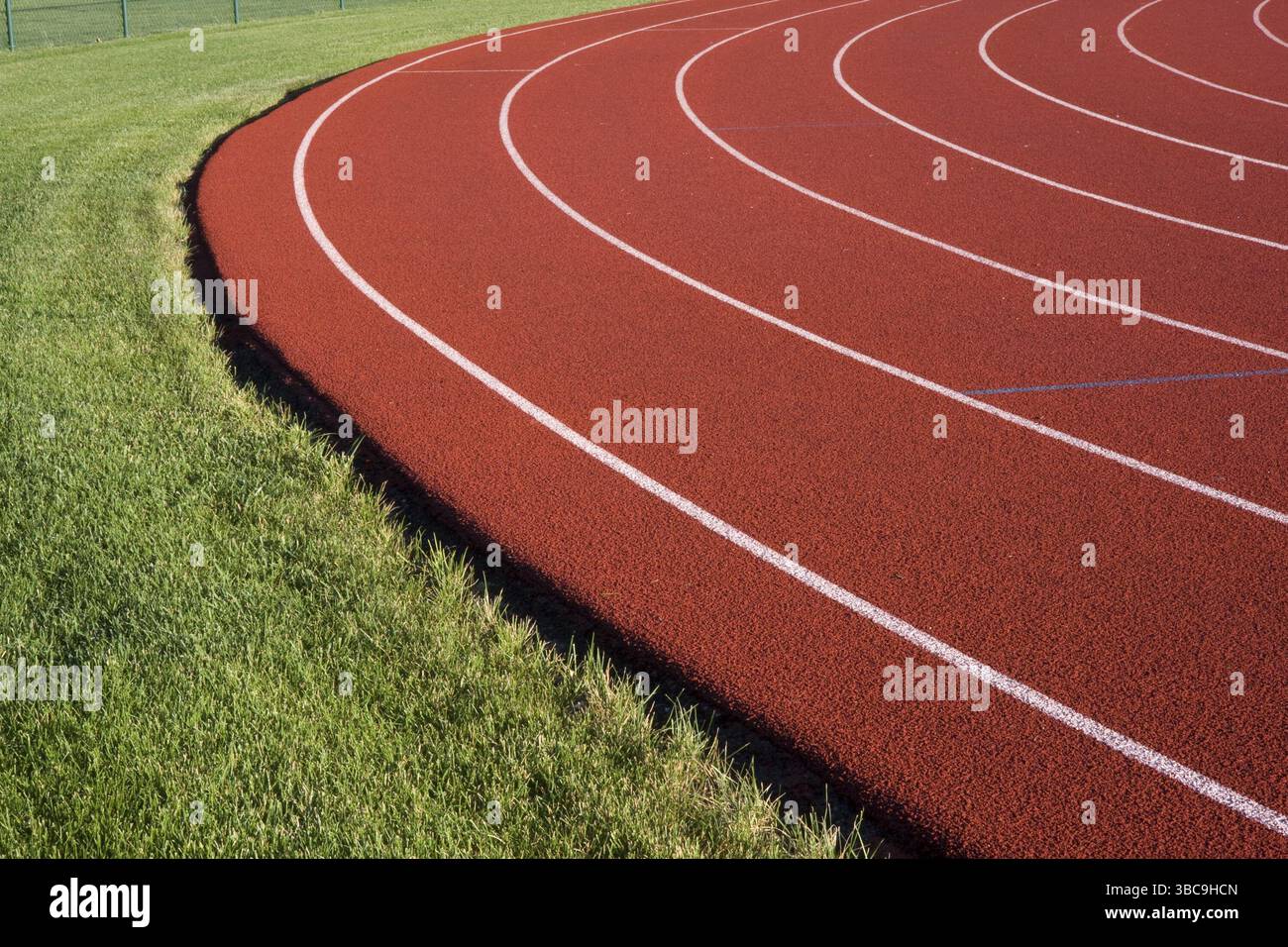 Running tracks with a red synthetic surface at a curve, green grass ...