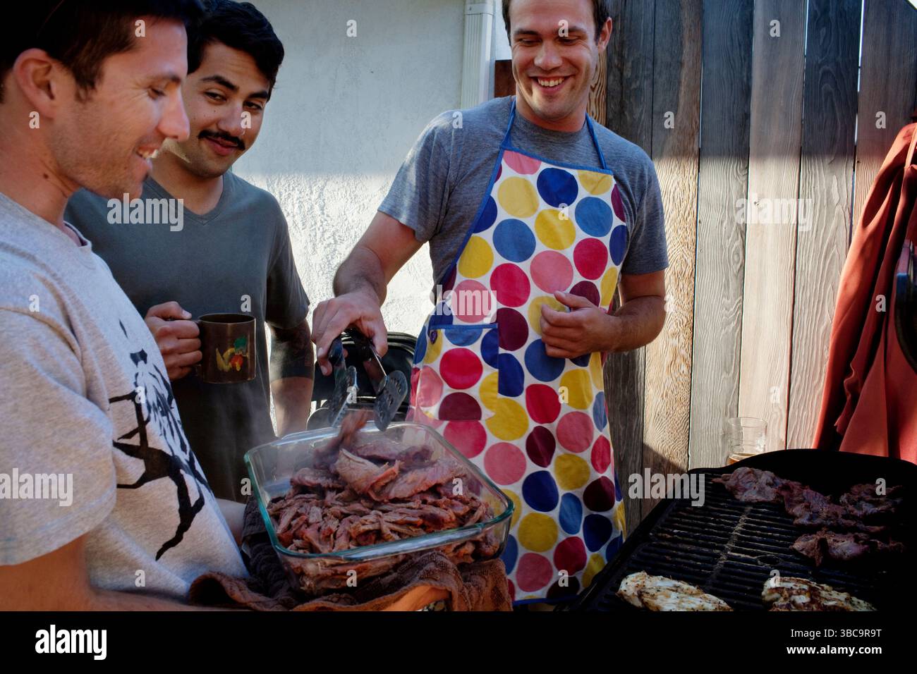 Three friends grill beef during a Fourth of July party in their ...