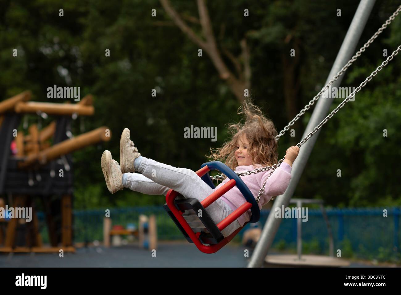 Side view of girl swinging in playground Stock Photo - Alamy