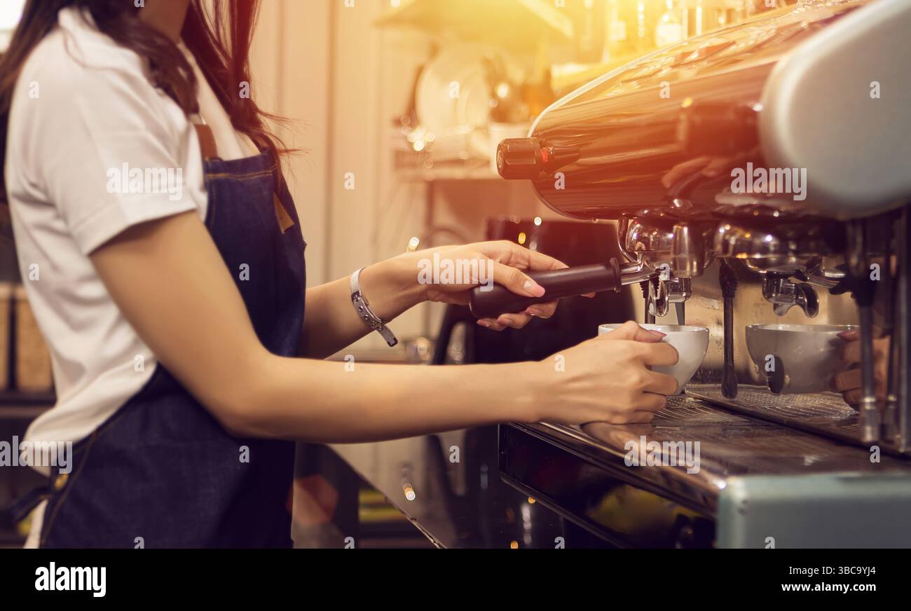 Hands of barista making coffee with espresso machine. Barista woman with apron preparing coffee ...