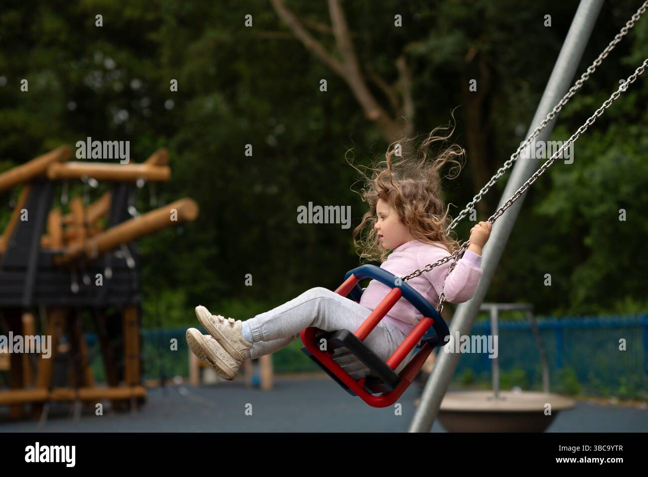 Side view of girl swinging in playground Stock Photo - Alamy