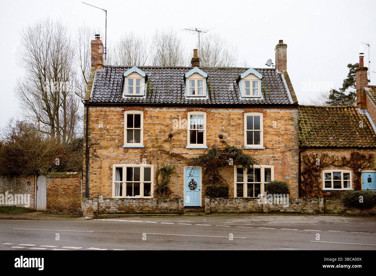 Brick house with blue door and dormer windows in Great Massingham Stock ...
