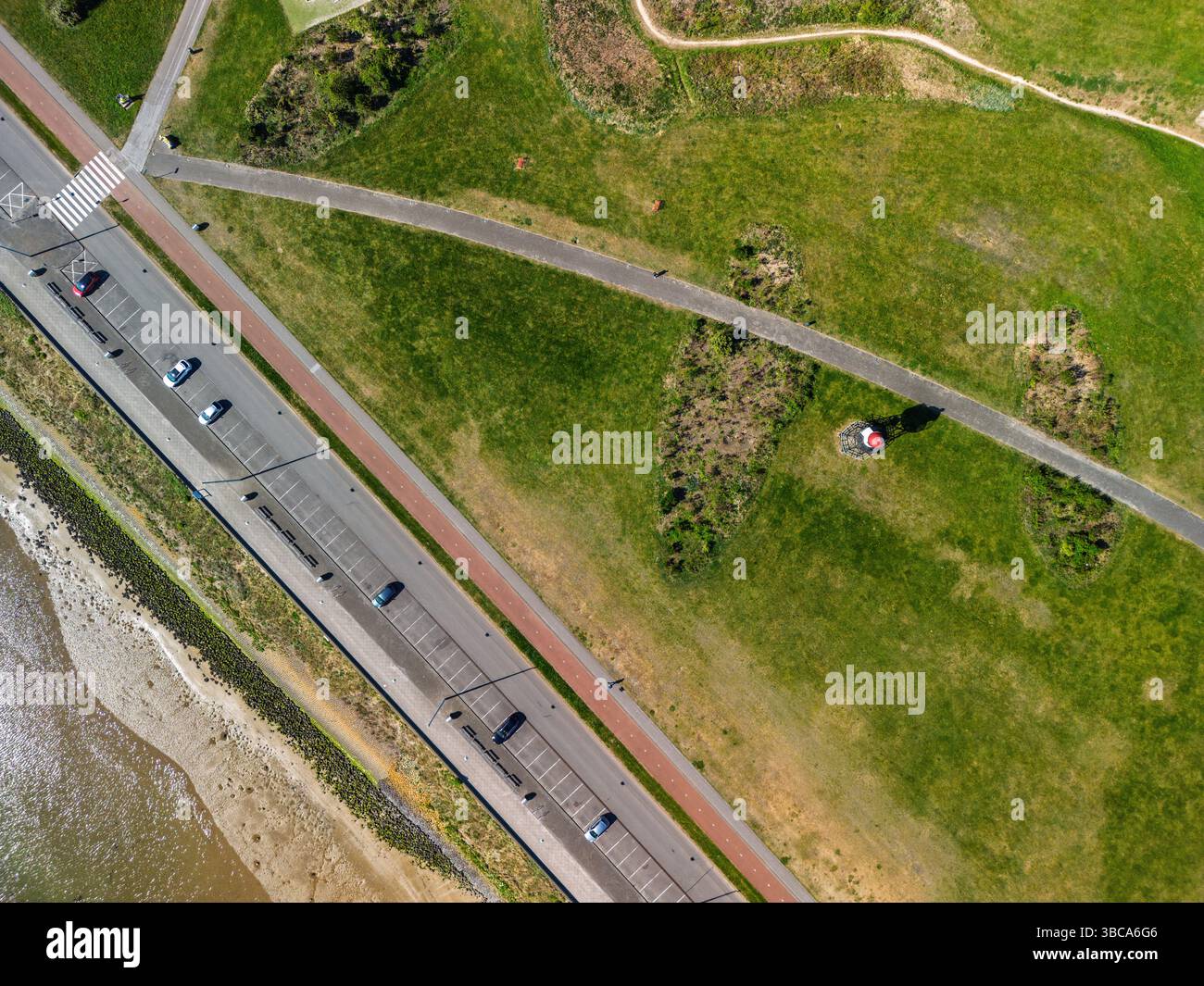 Aerial view of a coastal road with parked cars, a footpath through ...