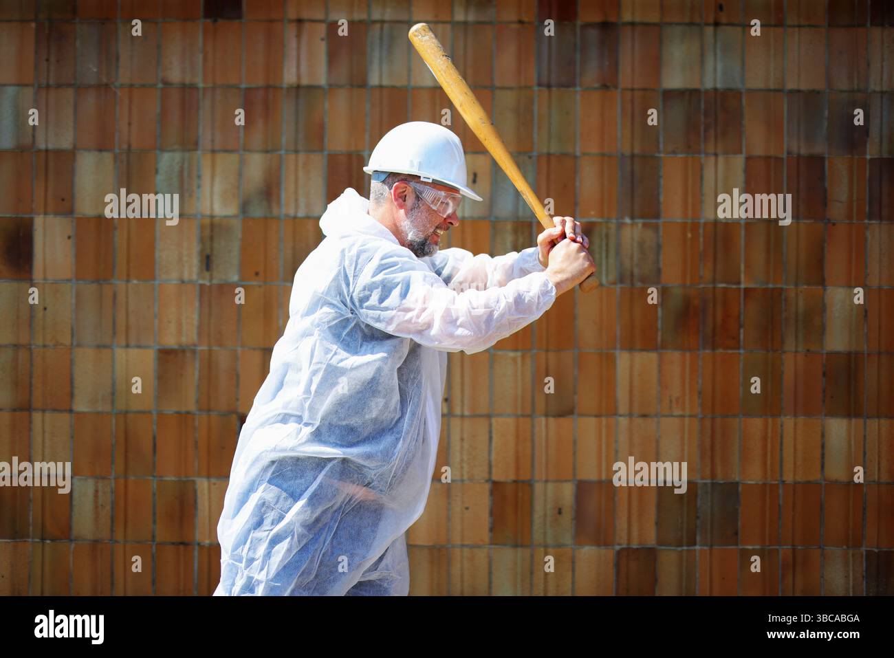 Man in full safety gear prepares to hit with baseball bat. Rage room or ...