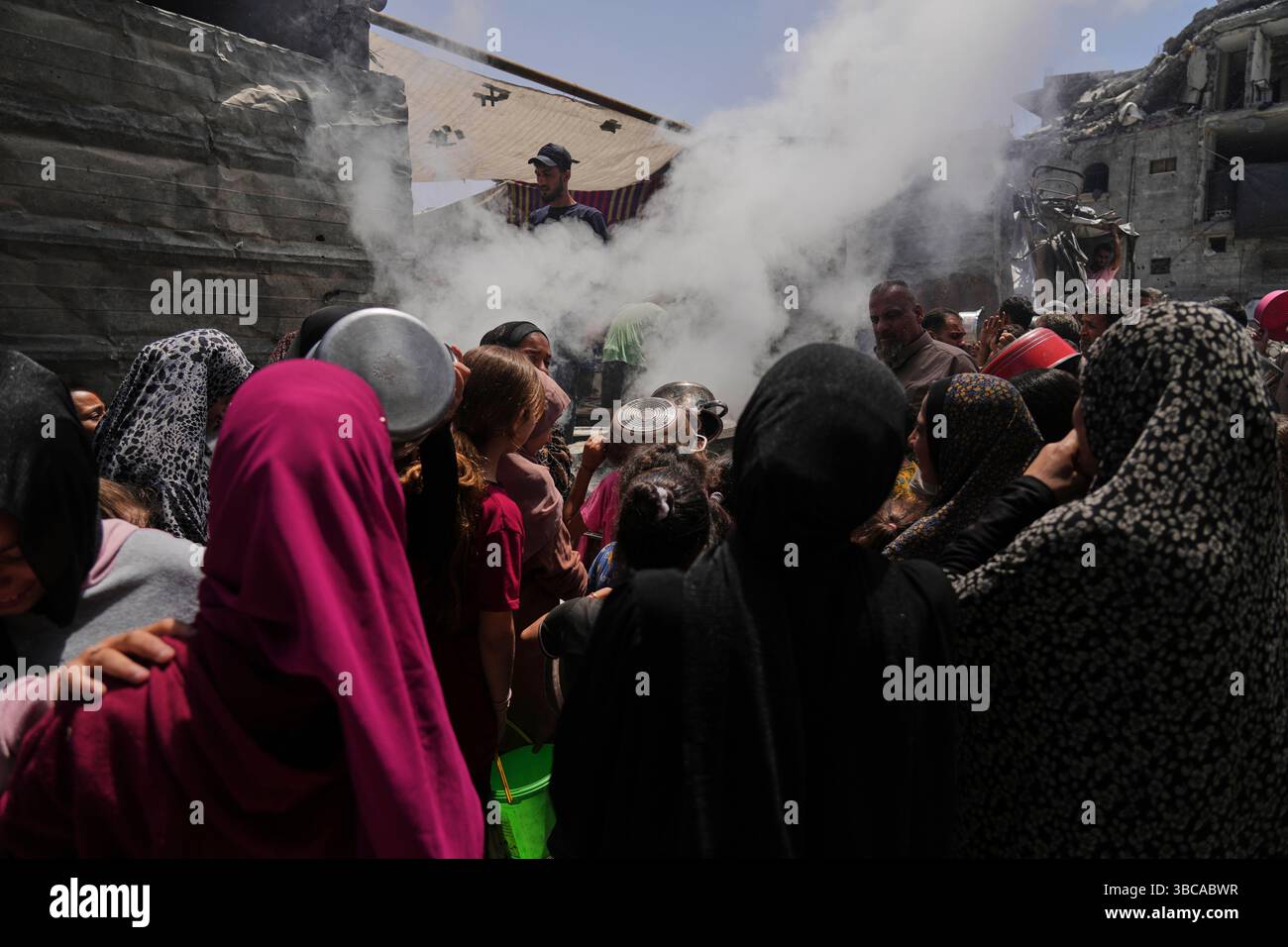 Palestinians line up for donated food at a community kitchen in Jabalia ...