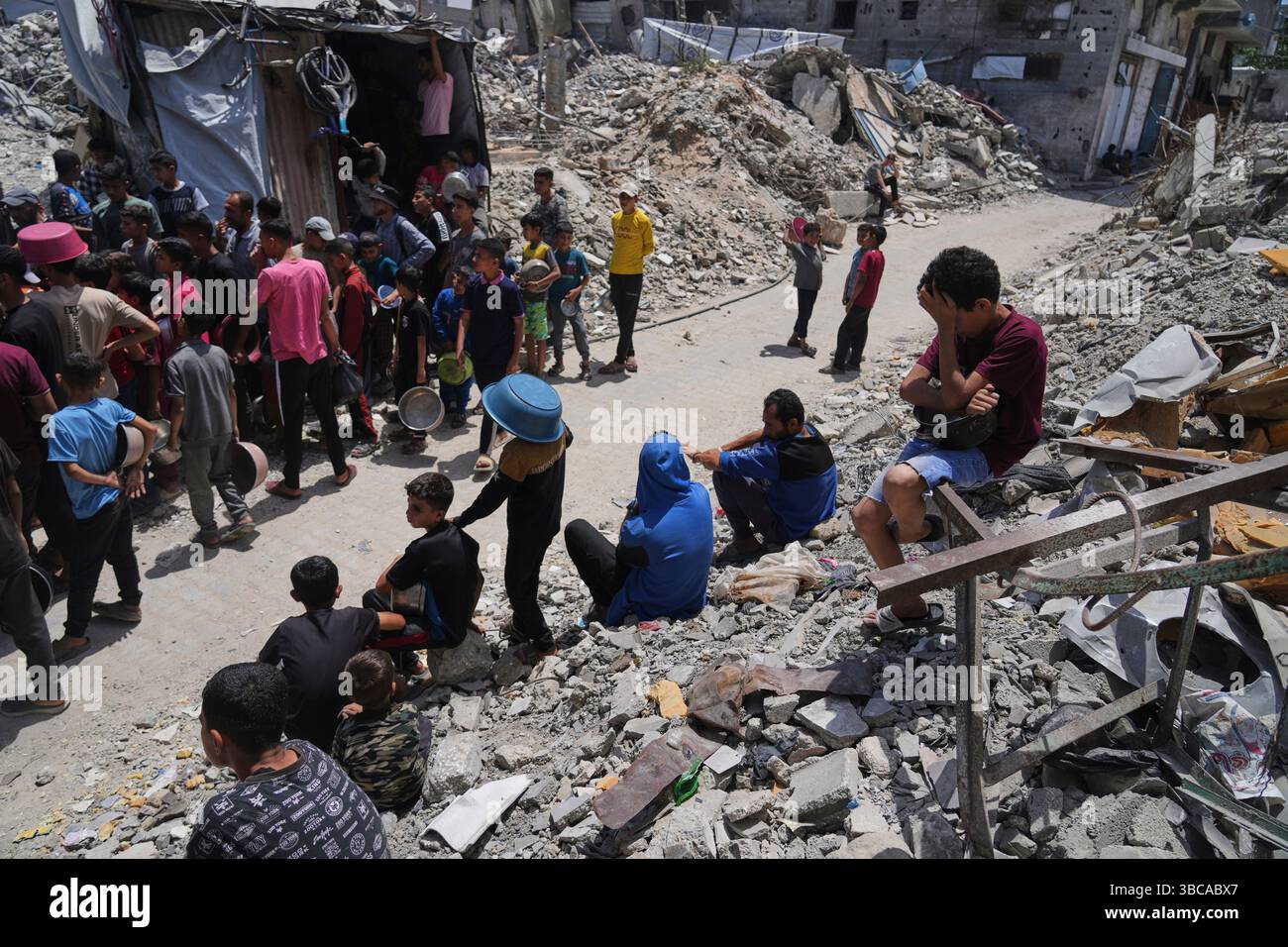 Palestinians line up for donated food at a community kitchen in Jabalia ...
