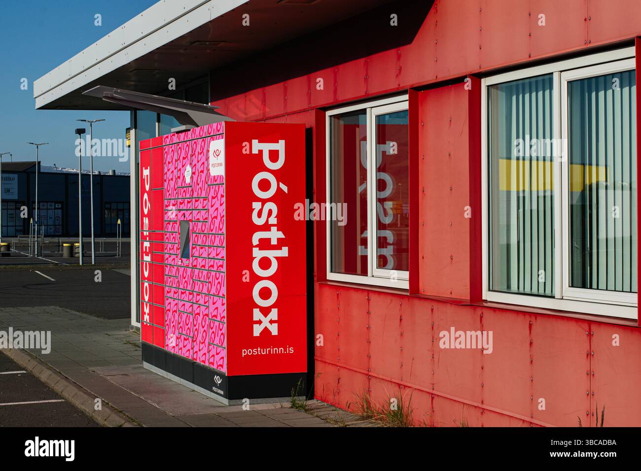 Akranes, Iceland - May 16, 2025: Red postal box next to a modern ...