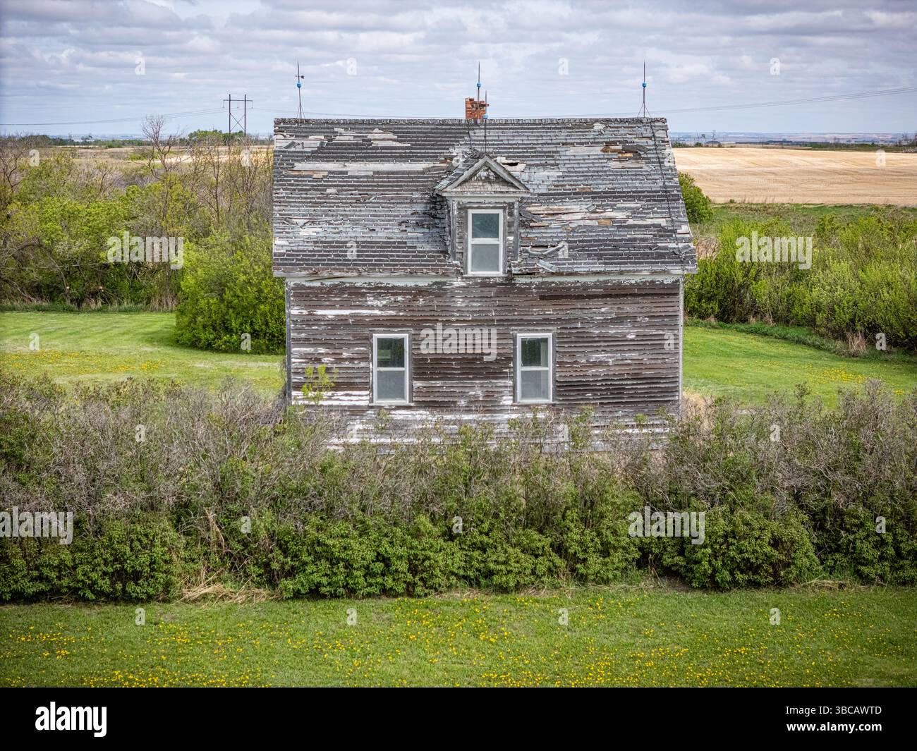Small, old house with a slanted roof sits in a field. The house is ...
