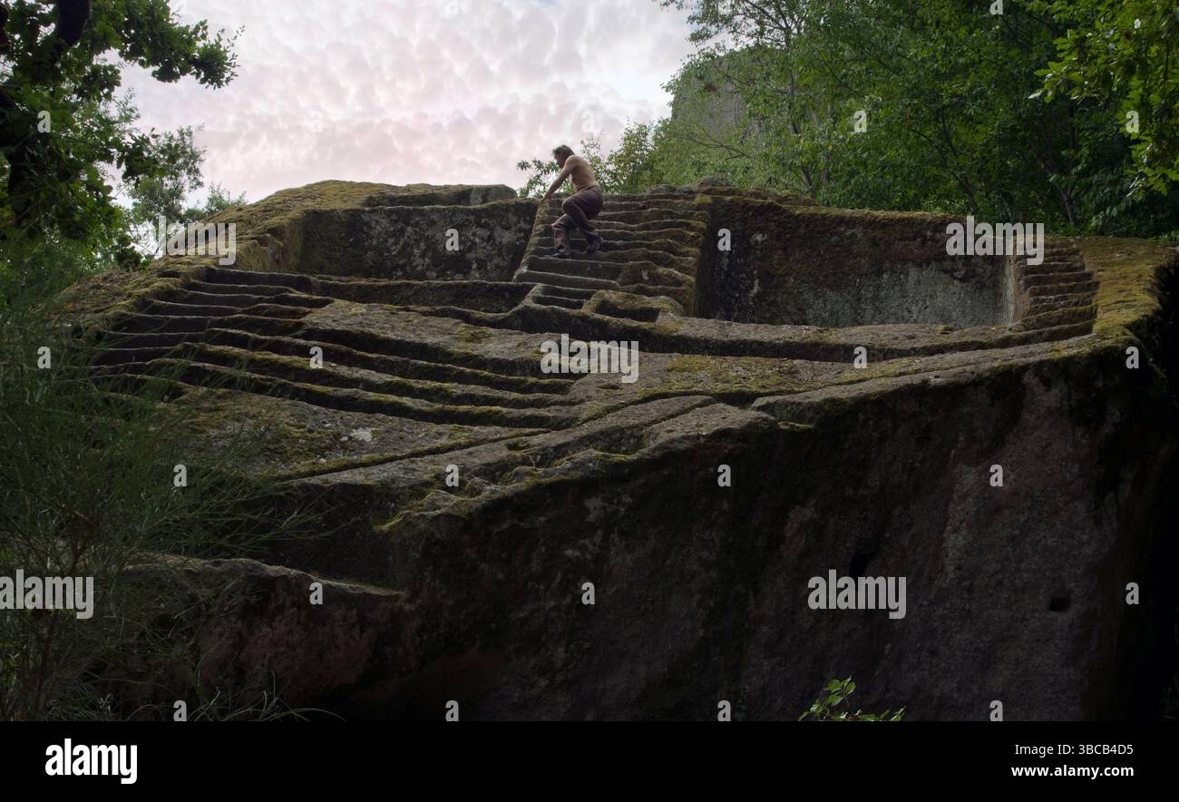 Man climbing the Etruscan pyramid in the Italian forest, Bomarzo, Italy ...