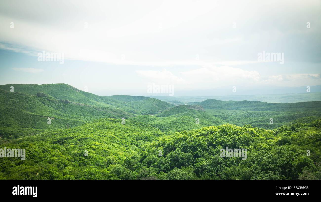 Vast green hills and a hidden lake under a clear sky in the Georgian ...