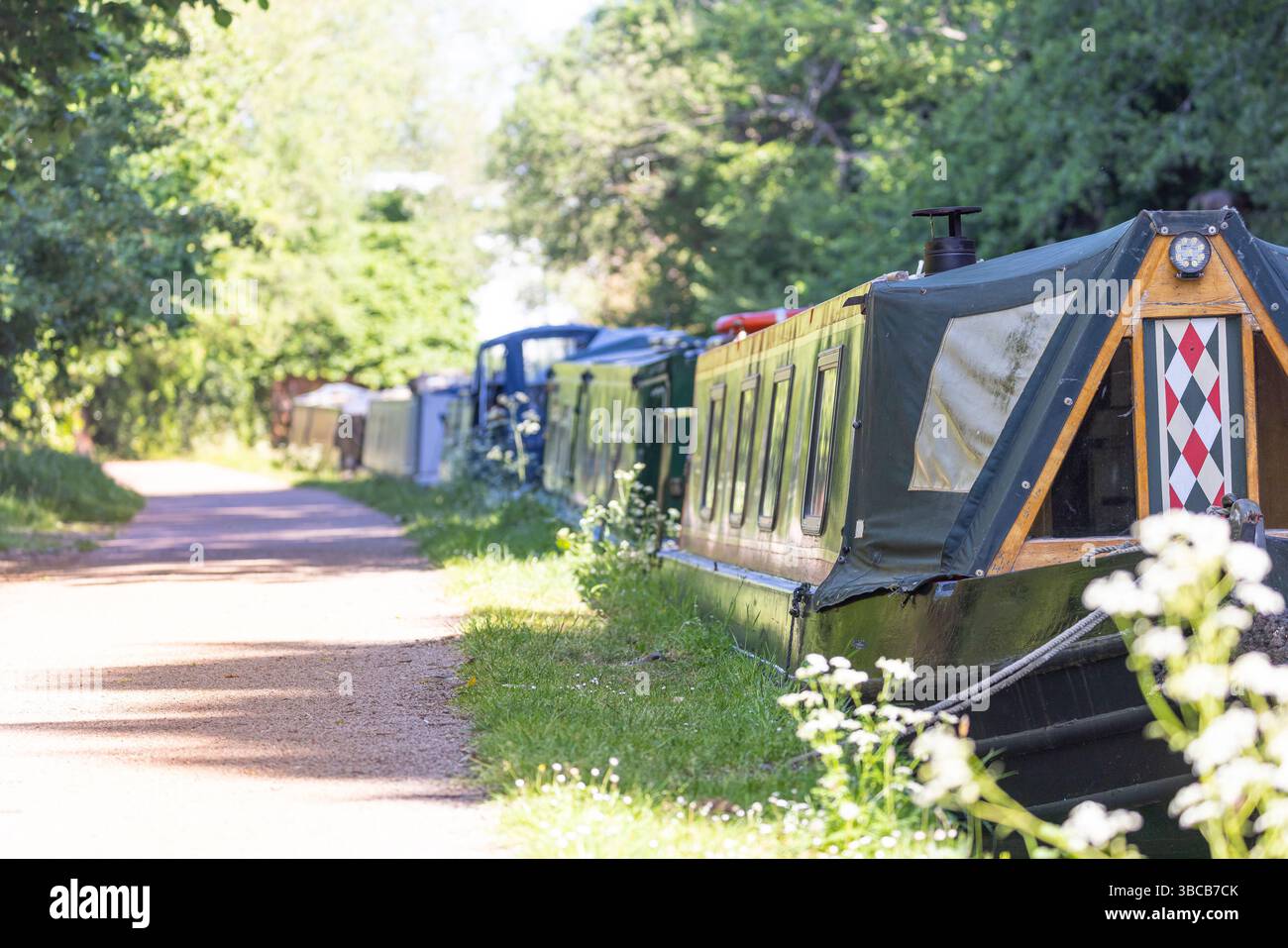 View of a number of narrow boat moored alongside a canal path with ...
