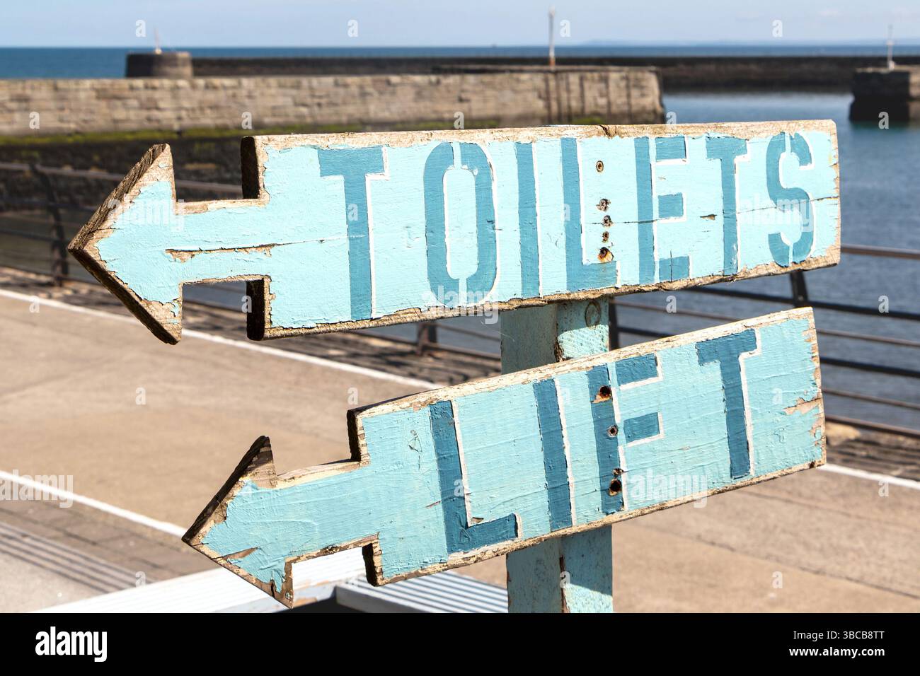 rustic Wooden directional signs pointing to public toilets and a lift ...
