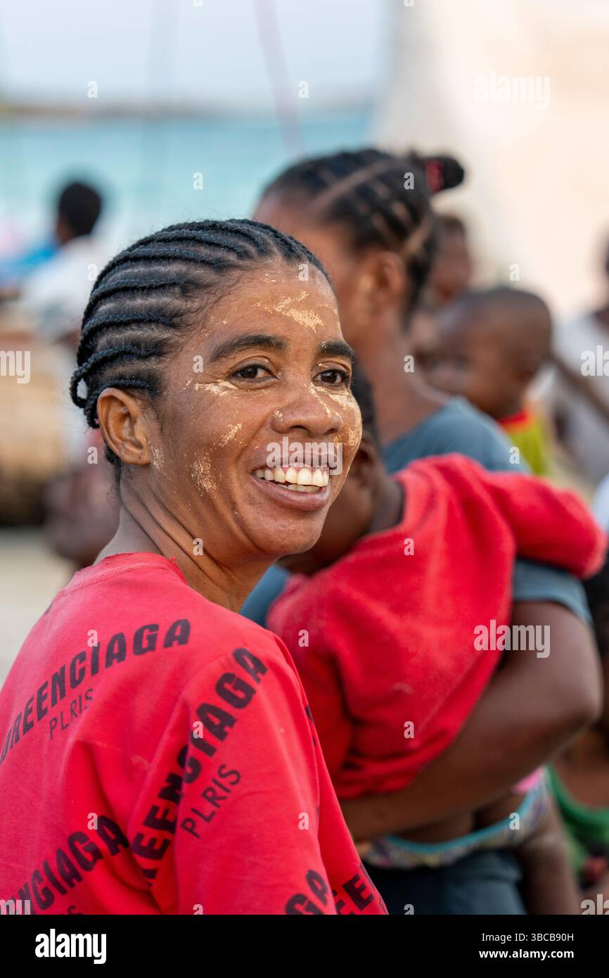 A smiling woman in a red shirt with traditional face mask makeup at the ...