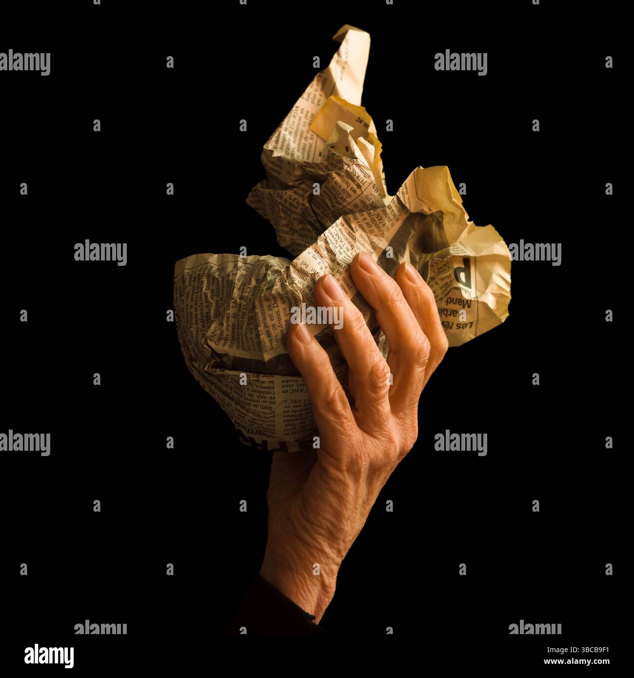 A hand grips a crumpled newspaper, illustrating a mix of emotions and ...