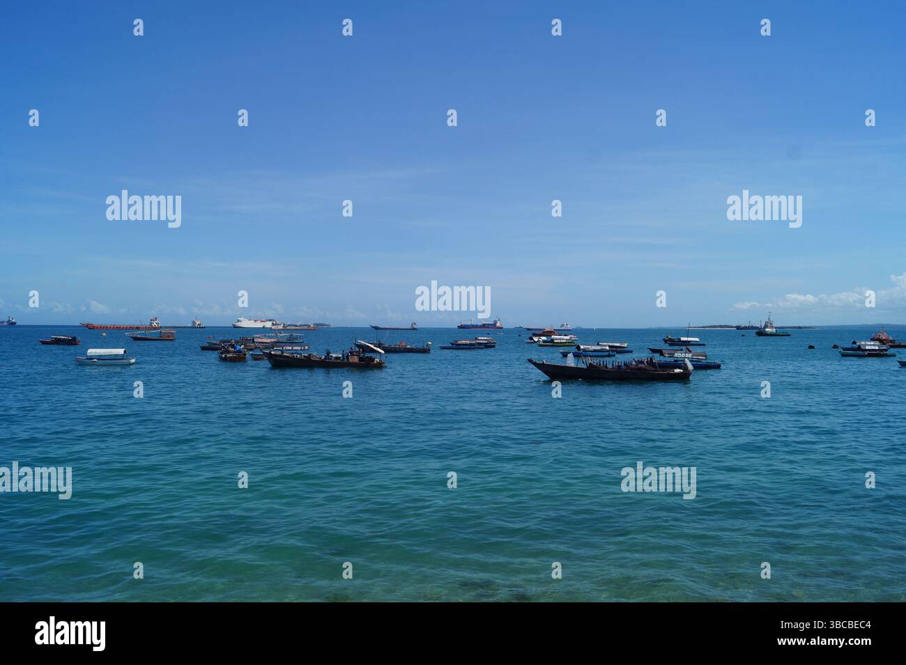 Traditional wooden dhow boats and larger cargo ships float on the ...