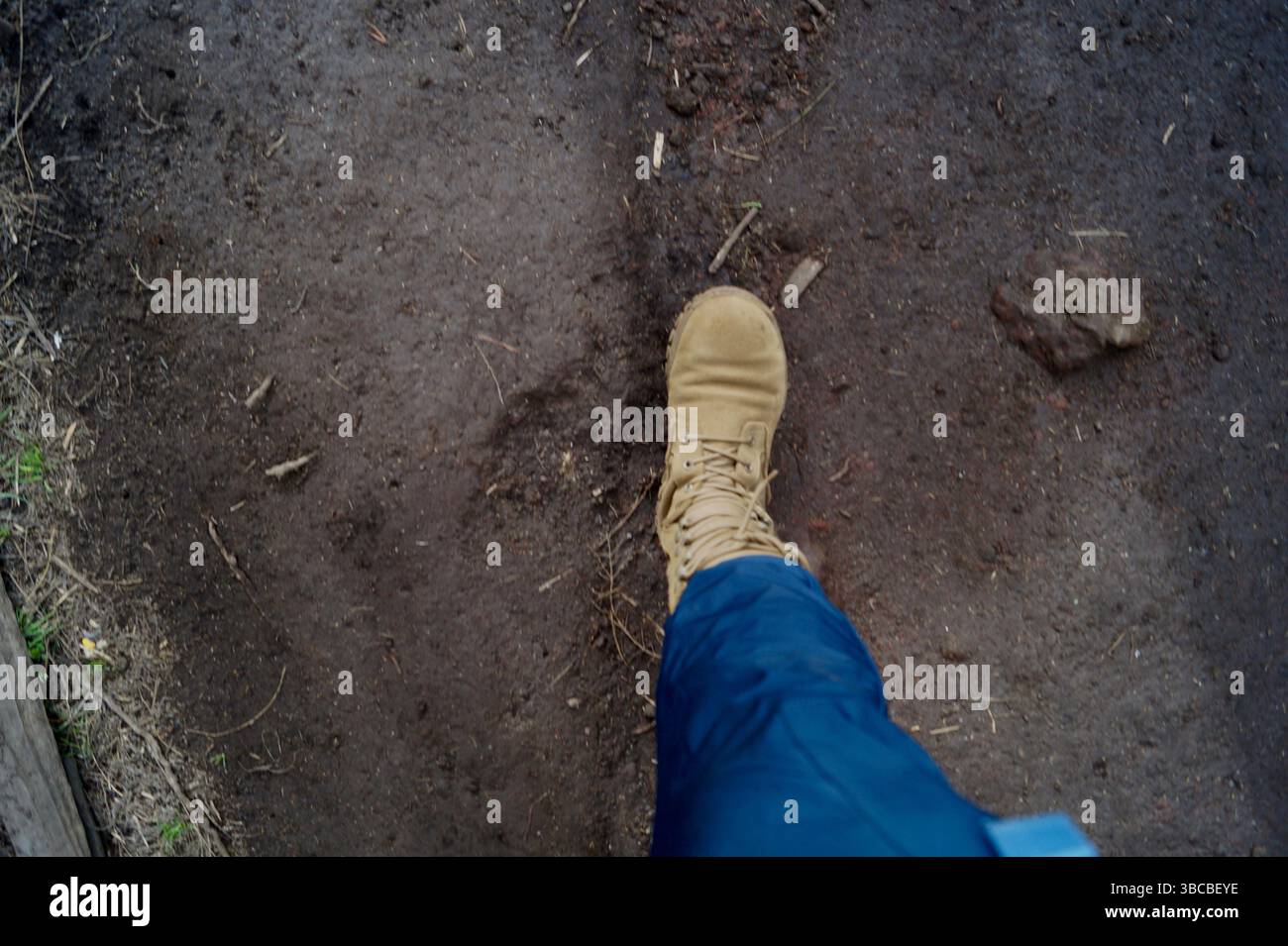 A single boot steps forward on a well-worn dirt trail, captured from a ...