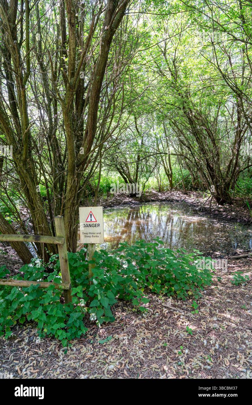 Danger deep water sign and pond surrounded by trees Stock Photo - Alamy