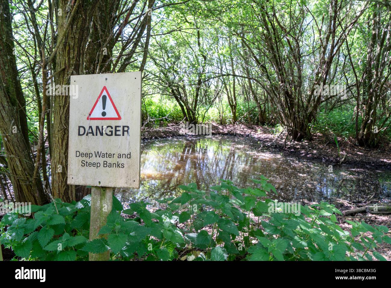 Danger deep water sign and pond surrounded by trees Stock Photo - Alamy