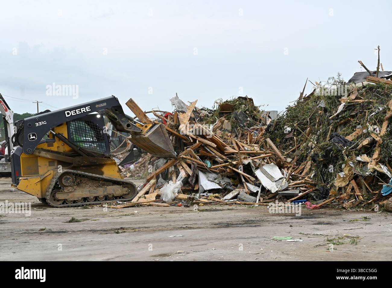 Workers pile debris from storm damage into piles for disposal at the ...