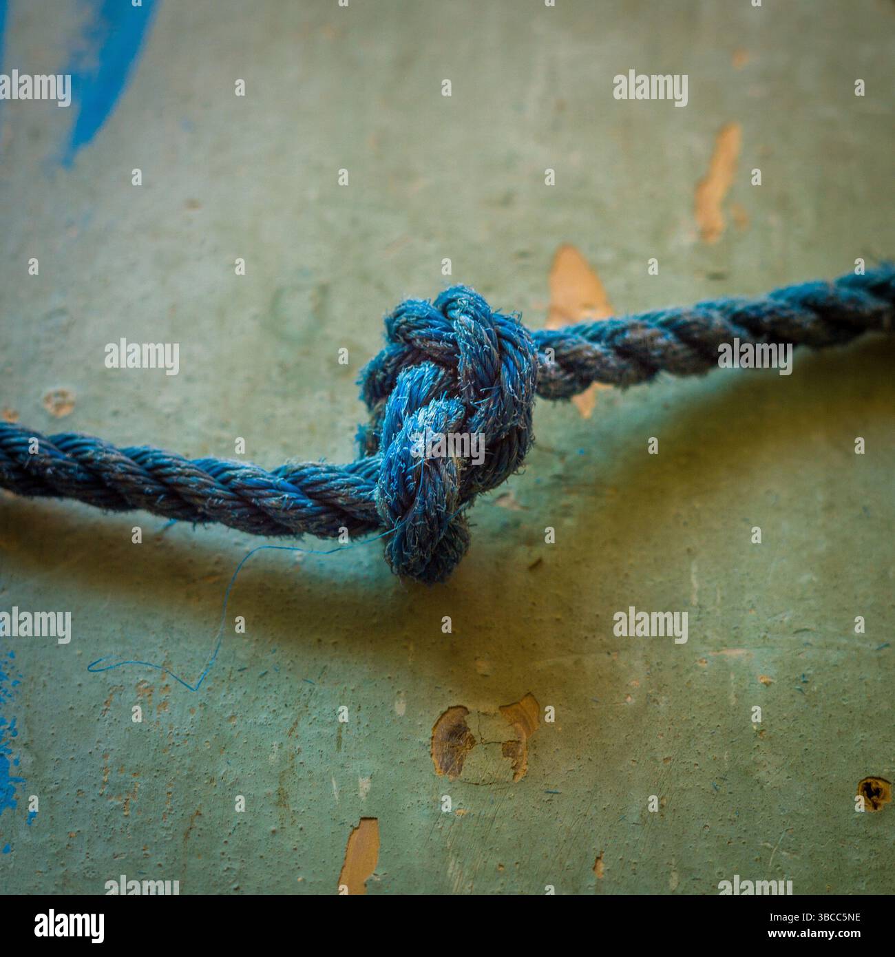 A close-up view reveals an intricately tied blue rope knot resting on a ...